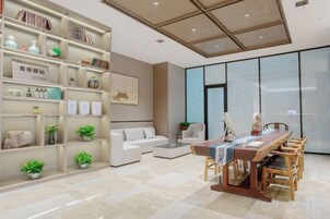 Uma sala de estar moderna com área de jantar, estante de livros e uma janela grande.