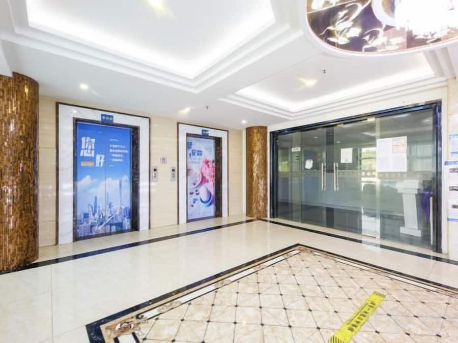 Um saguão de hotel com piso lustroso, um balcão de recepção e dois elevadores.