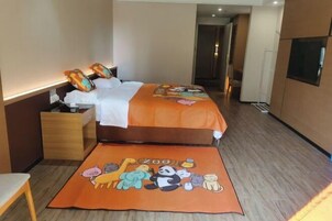 Quarto de hotel com cama, mesas de cabeceira, uma janela e televisão fixada na parede.