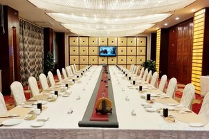 Uma sala de conferência com uma mesa comprida, cadeiras e uma tela de televisão.