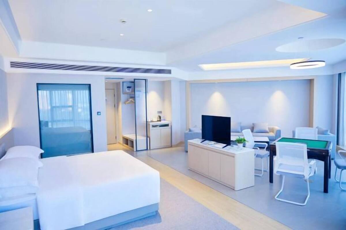 Quarto de hotel moderno com cama, escrivaninha, televisão e mesa de bilhar.