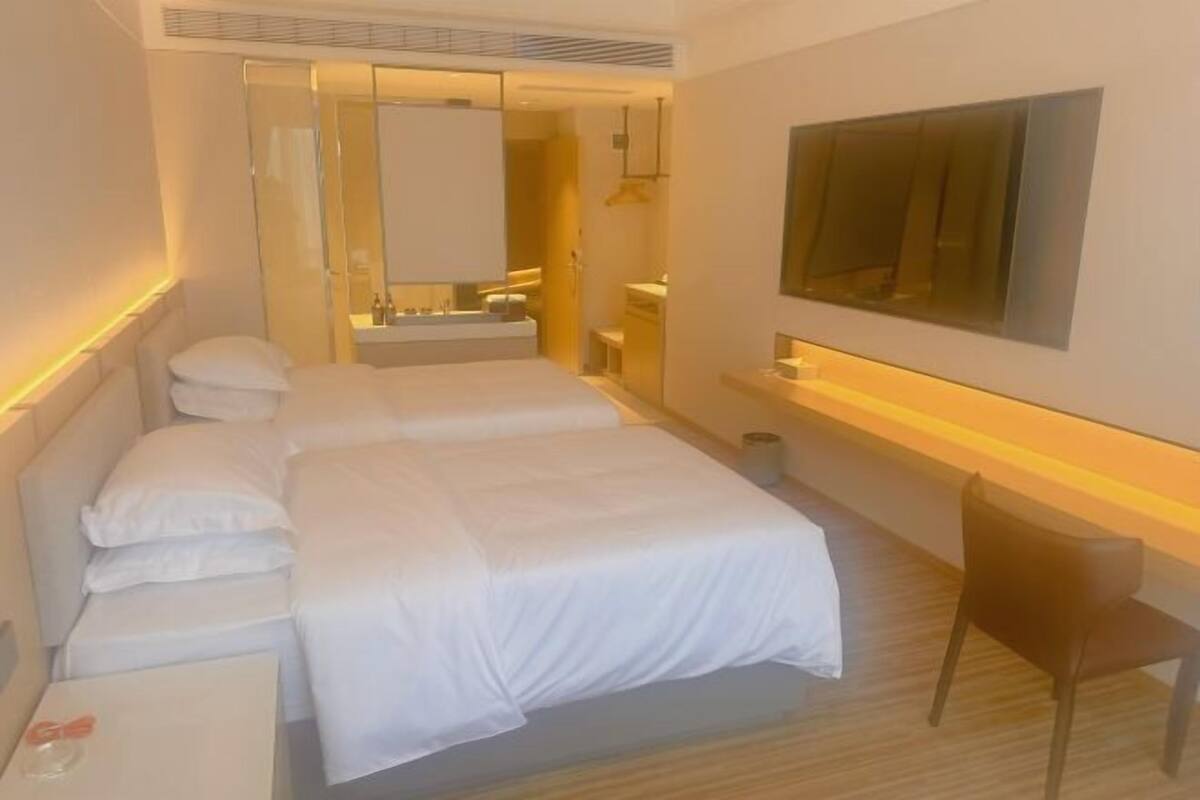 Quarto de hotel com cama, uma cadeira, escrivaninha e espelho.