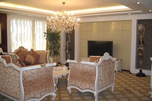 Uma sala de estar ampla com móveis elaborados, um candelabro e uma televisão.
