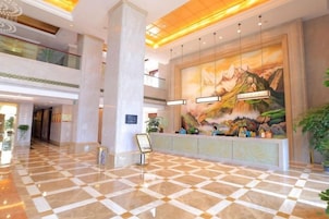 Um hall com chão quadriculado, um balcão de recepção e um grande mural.