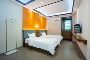 Quarto de hotel moderno com duas camas, televisão e claraboia.