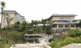 Um edifício em estilo tradicional chinês, com um jardim, um lago e uma ponte.