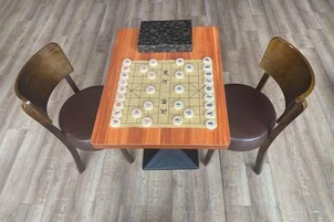 Uma mesa de madeira com um jogo de tabuleiro quadriculado, duas cadeiras e um objeto preto sobre a mesa.