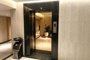 Um elevador com design moderno, uma lixeira e um vaso de plantas.