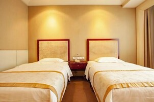 Quarto de hotel com duas camas, uma mesa de cabeceira e um telefone fixado na parede.