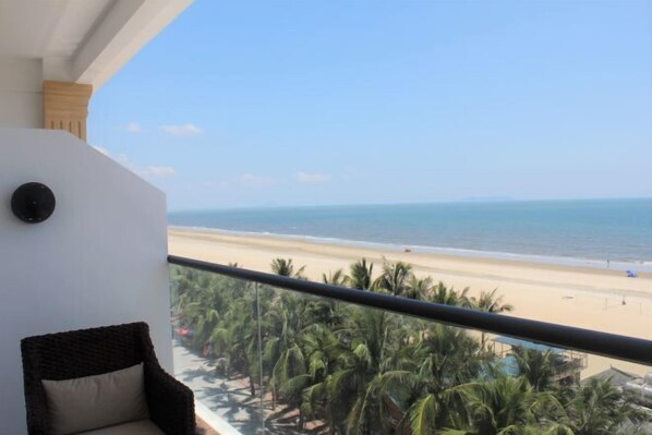 Uma varanda com vista para a praia e palmeiras.
