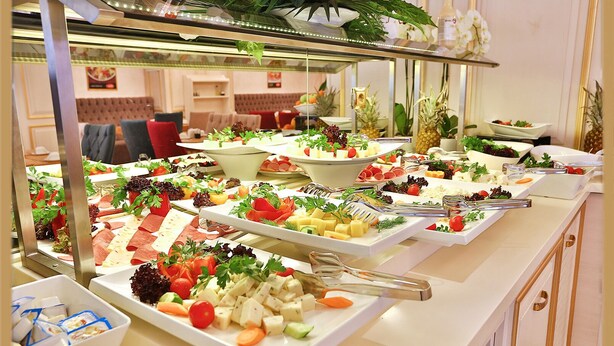 Buffet com diversos alimentos, incluindo carnes, queijos e saladas.