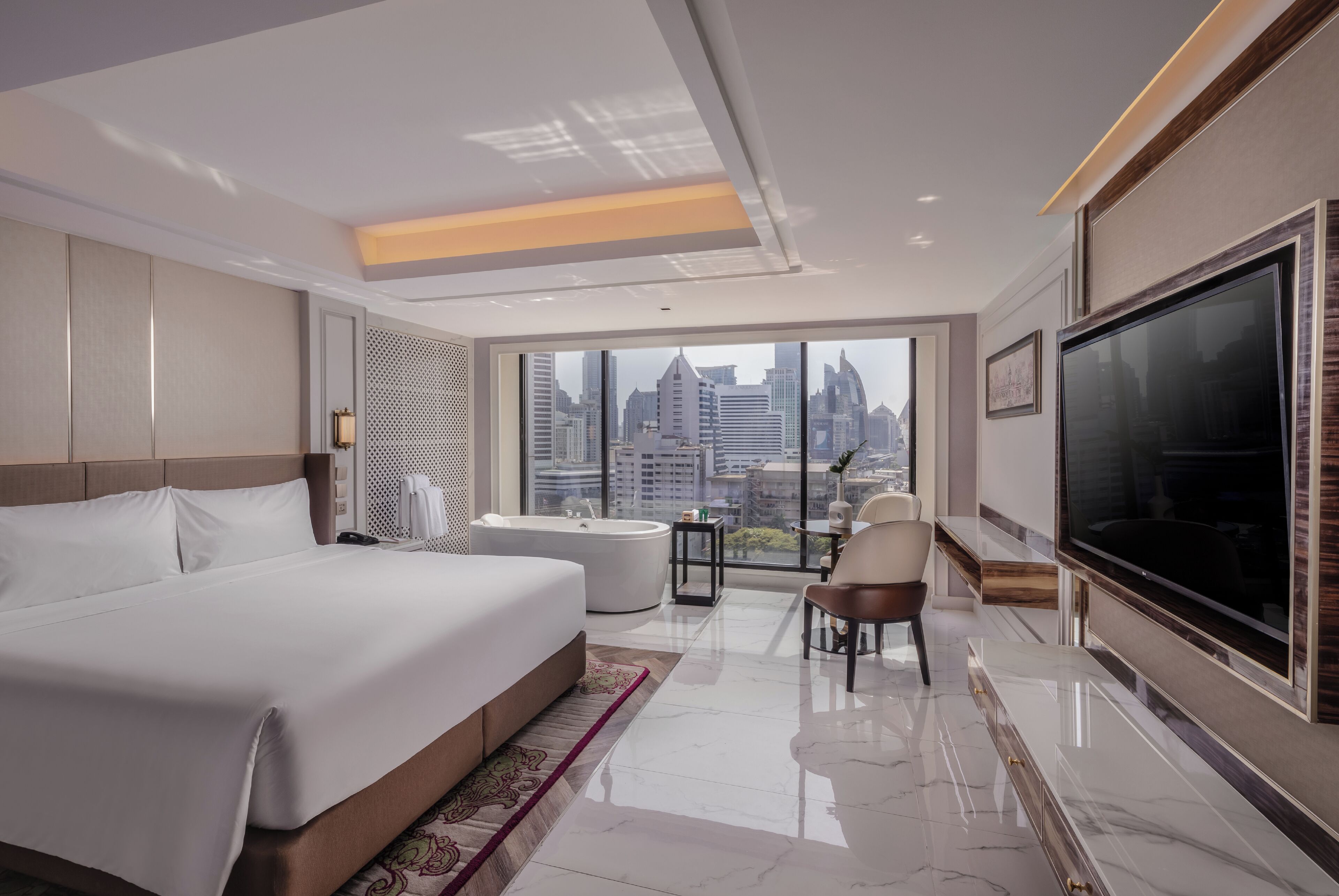 Quarto de hotel moderno com uma cama grande, área de estar, TV e vista para a cidade.