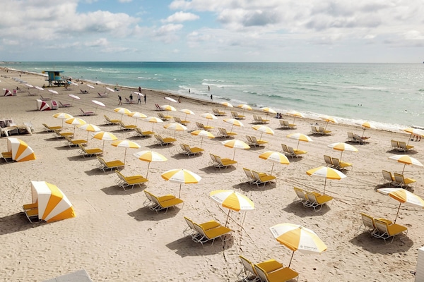 Perto da praia, areia branca, espreguiçadeiras, toalhas de praia