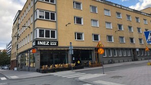 Um edifício com vários andares, com um bar chamado "INEZ TAPAS BAR" no andar térreo.