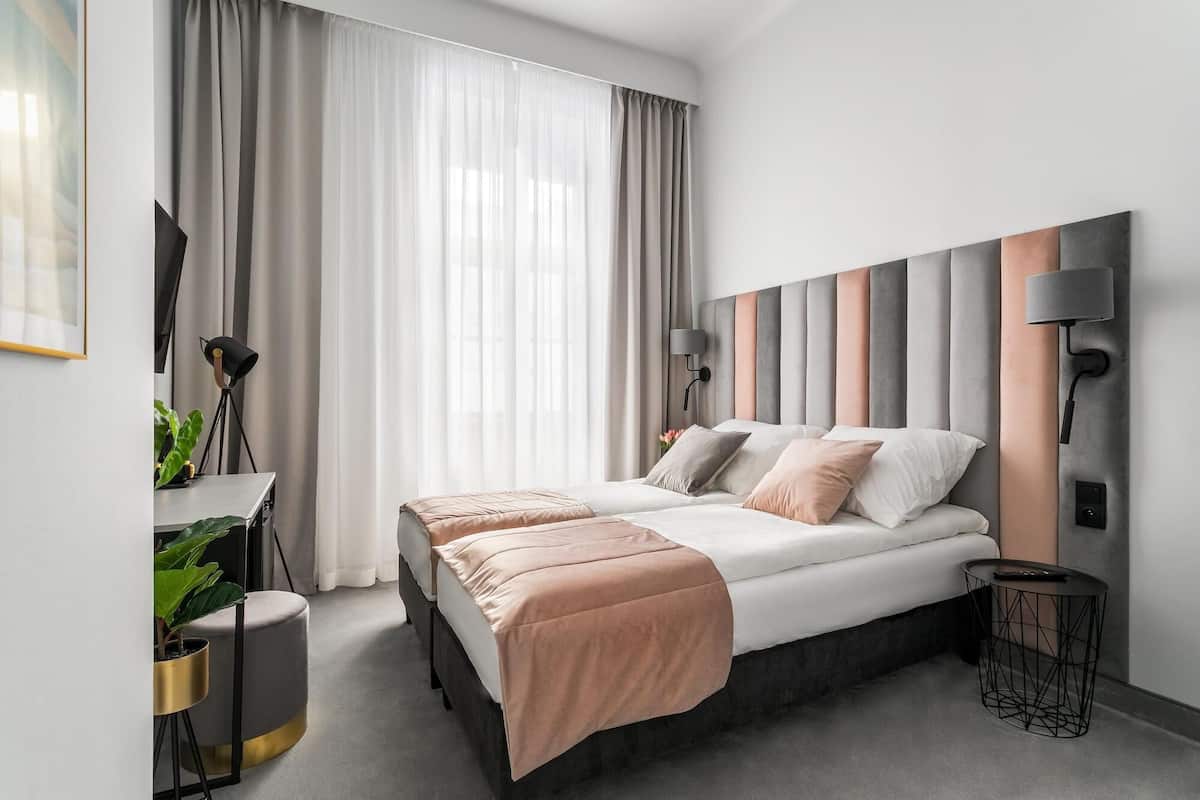 Quarto moderno com cama, abajures, escrivaninha e planta em vaso.