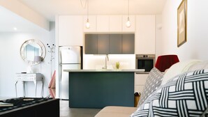 Cozinha moderna com ilha central, armários brancos e iluminação pendente.