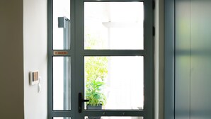 Uma porta moderna com placa de 'Proibido Fumar', um vaso de planta e vista para o exterior.