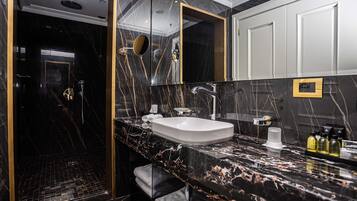 Casa de banho moderna com bancada de mármore preto, lavatório branco e espelho grande.