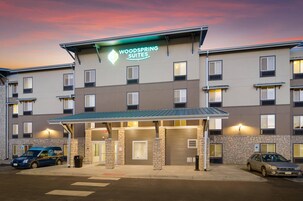 Um hotel com vários andares, com uma placa indicando 'Woodspring Suites' e entrada coberta.