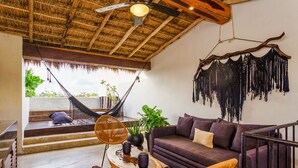 Uma sala de estar com uma rede, um sofá e uma peça decorativa de macramé.
