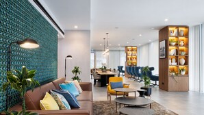 Uma sala de estar moderna com um sofá marrom, uma poltrona amarela e uma área de jantar com cadeiras azuis.