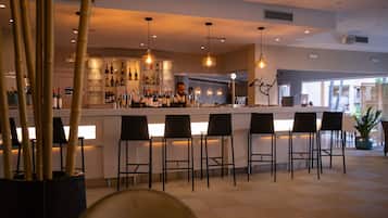 Uma área de bar com balcão, vários bancos e uma variedade de garrafas e copos.
