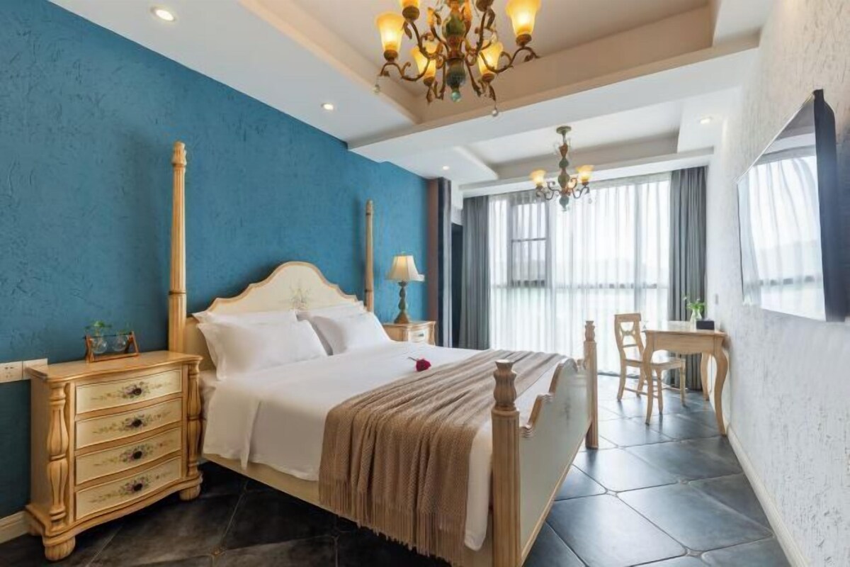 Um quarto com uma cama, mesas de cabeceira, uma escrivaninha e uma cadeira.