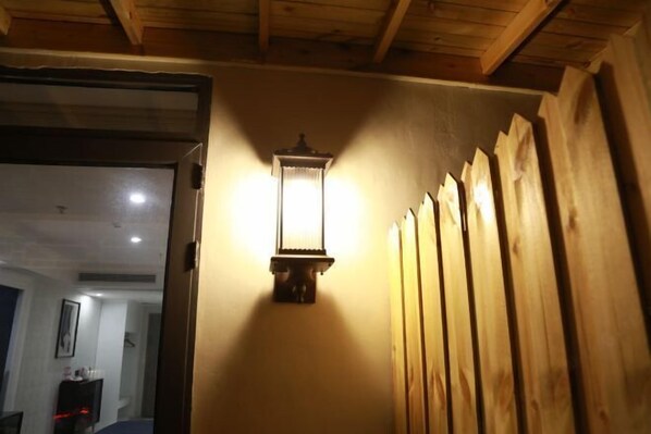 Um corredor com luminária na parede e lambrisagem de madeira.