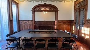 Uma sala de conferências com uma mesa comprida e cadeiras, painéis de madeira e um teto decorativo.