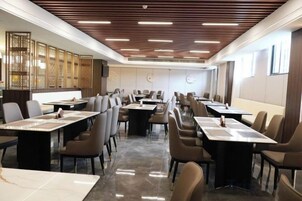 Uma sala de conferências com mesas e cadeiras compridas, teto de madeira e um relógio na parede.