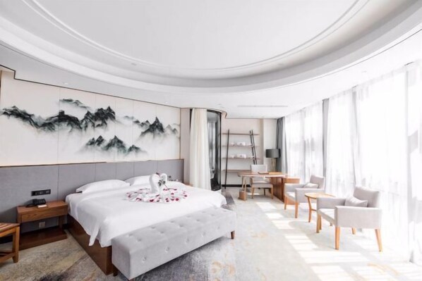 Quarto de hotel moderno com uma cama grande, uma escrivaninha e um espaço de estar.