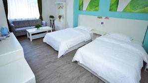 Quarto de hotel com duas camas, um sofá, uma mesa de centro e uma escrivaninha.