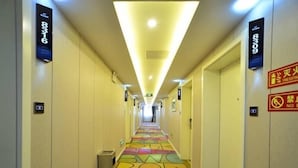 Corredor de hotel com portas numeradas, aviso de extintor de incêndio e placa de proibido fumar.