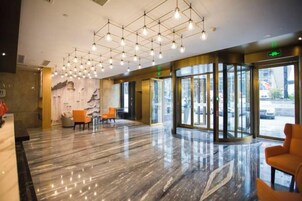 Um hall de hotel com piso de mármore, área de estar e portas de vidro que dão para o exterior.