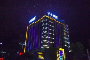 Um edifício de vários andares com sinalização iluminada e linhas verticais.