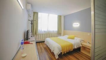 Quarto de hotel com cama, mesa de cabeceira e janela com cortinas.