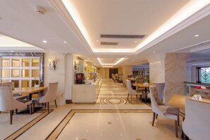 Um hall de hotel com recepção central, várias áreas de estar e piso de mármore.