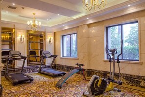 Academia de hotel com esteiras, bicicleta ergométrica e banco.