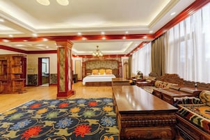 Quarto espaçoso com uma cama grande, uma escrivaninha de madeira, um sofá e um tapete estampado.
