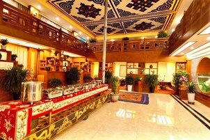 Um saguão de hotel com uma mesa de recepção, área de buffet e teto decorativo.
