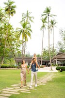 Uma trilha com palmeiras e um edifício ao fundo.