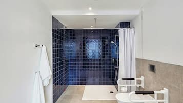 Uma casa de banho moderna com chuveiro, sanita e um porta-toalhas.