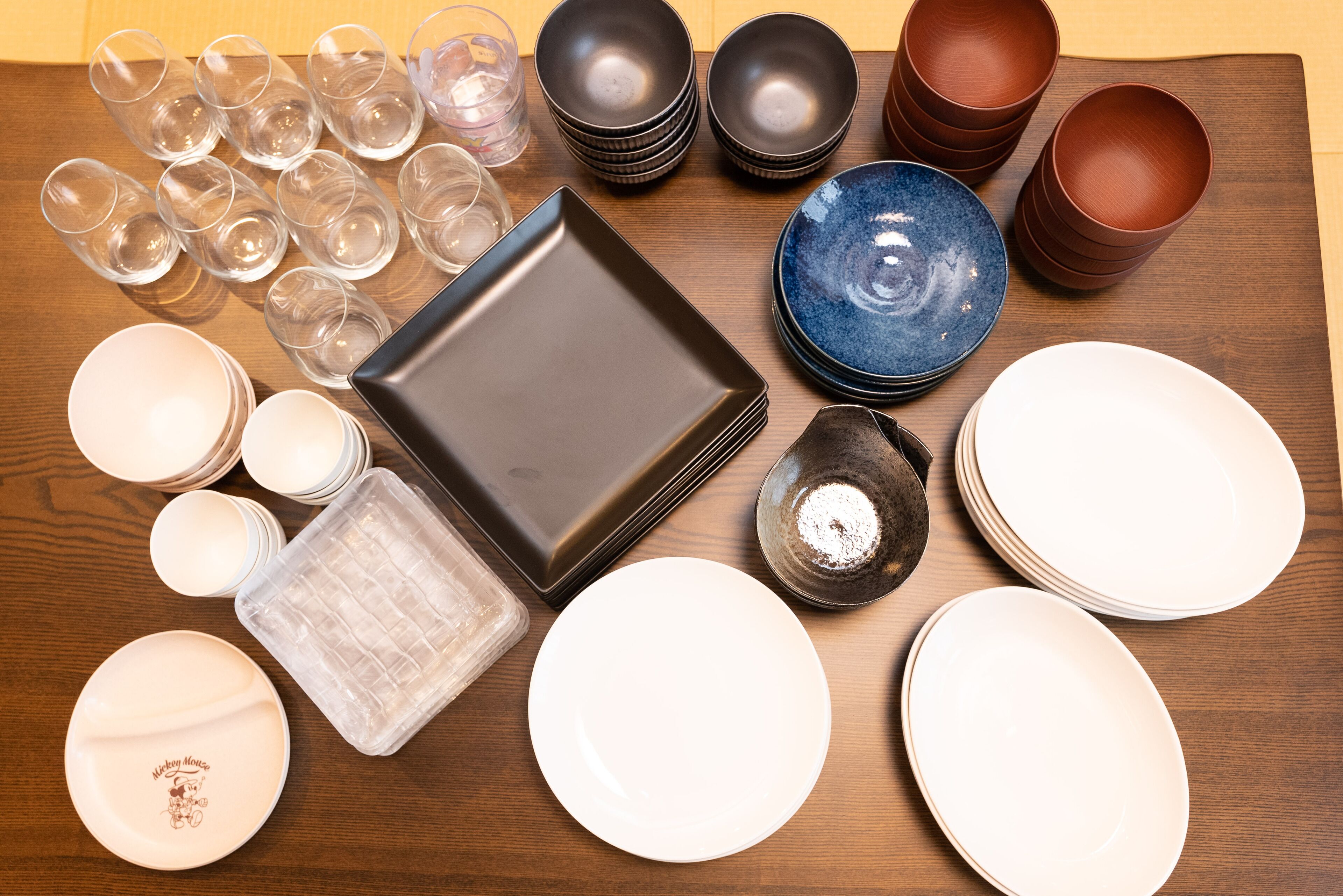 Diversos utensílios de mesa, incluindo pratos, tigelas, copos e uma bandeja.