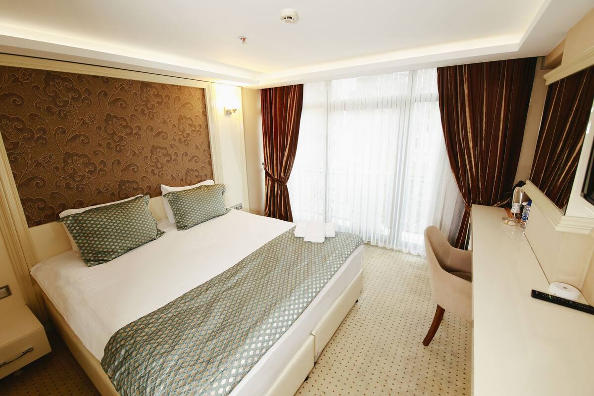 Quarto de hotel com uma cama grande, uma escrivaninha e uma cadeira.