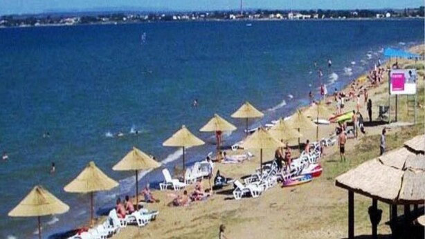 Uma praia com guarda-sóis, espreguiçadeiras e vista para o mar.