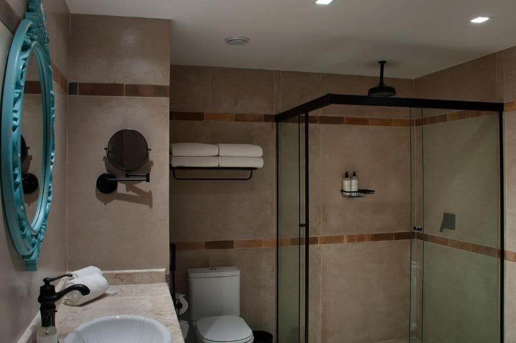 Uma casa de banho moderna com cabine de duche em vidro, sanita e lavatório com espelho.