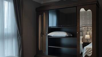 Quarto de hotel com um guarda-roupa espaçoso, uma cama e uma mesa de cabeceira com abajur.