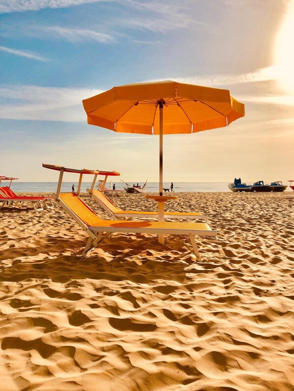 Uma praia com espreguiçadeiras e um guarda-sol.
