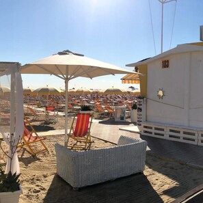 Um hotel à beira-mar com área de estar externa, guarda-sóis e vista para a praia.