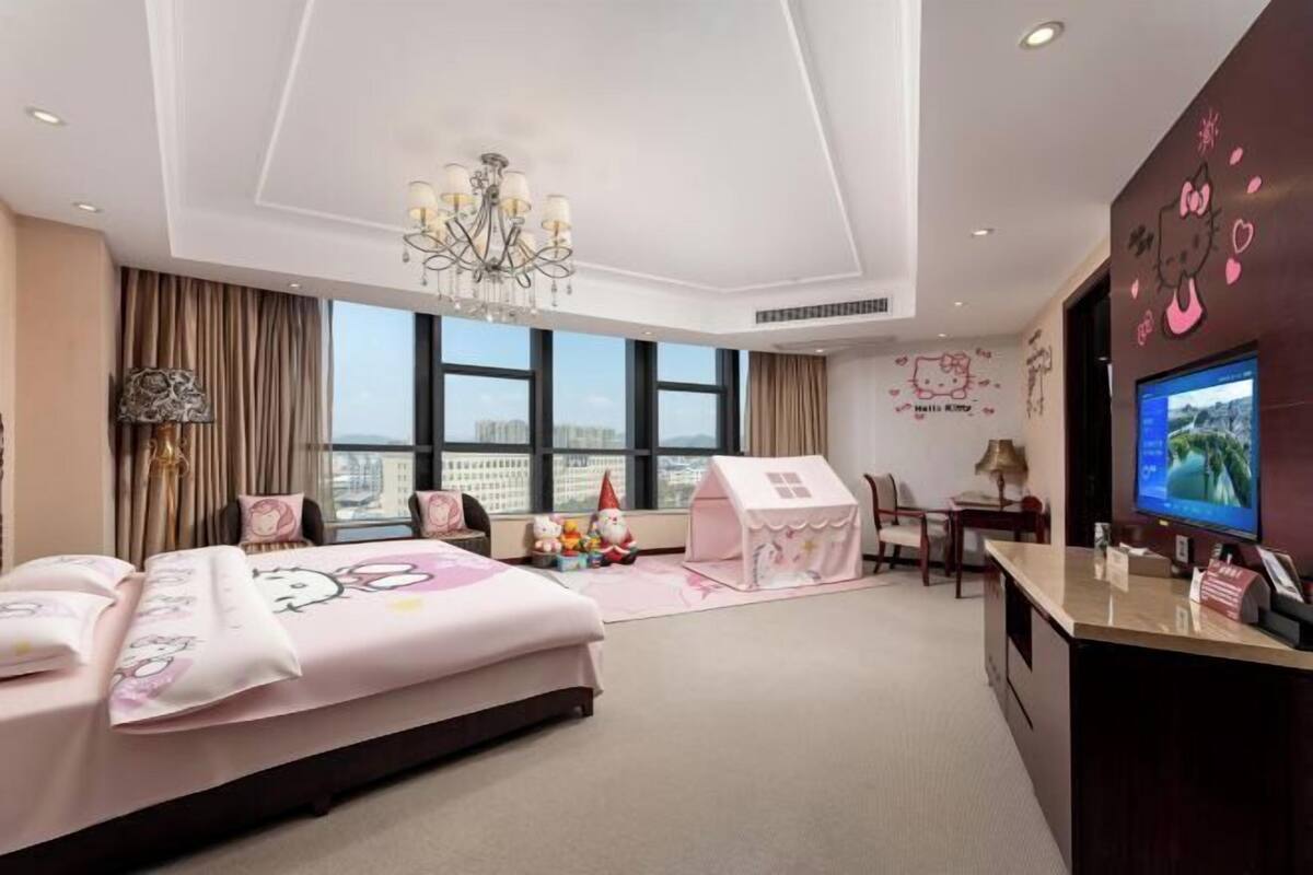 Quarto de hotel com uma cama grande, uma escrivaninha, televisão e vista para a cidade.